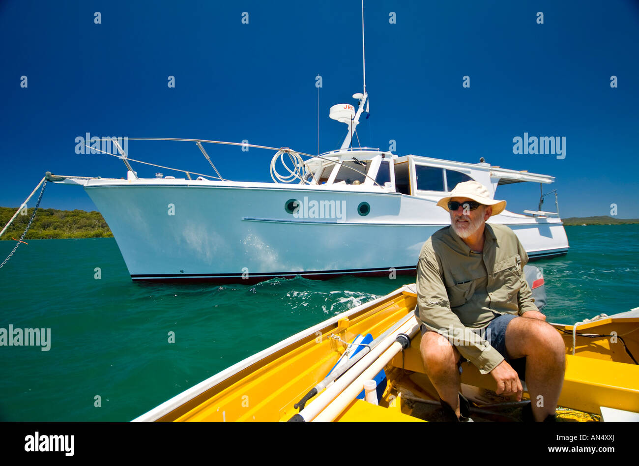 Man in dinghy next to a larger boat Stock Photo - Alamy