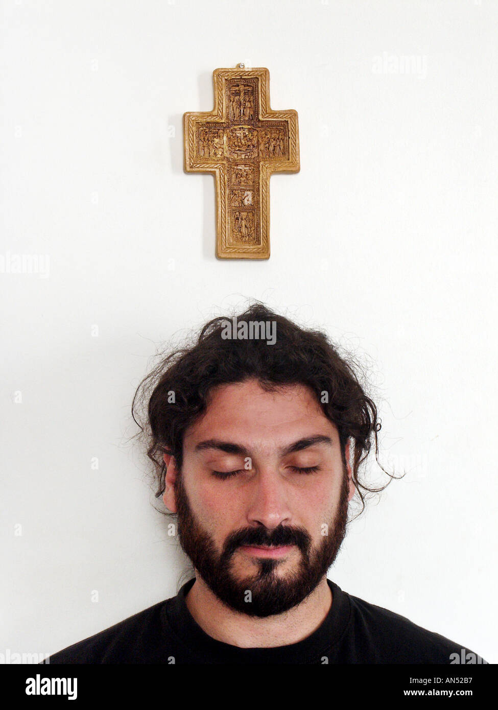 Man's head under cross hanging on the wall eyes shut praying Stock ...