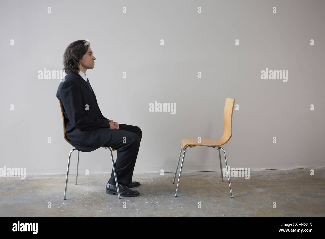 Businessman sitting across from empty chair Stock Photo - Alamy