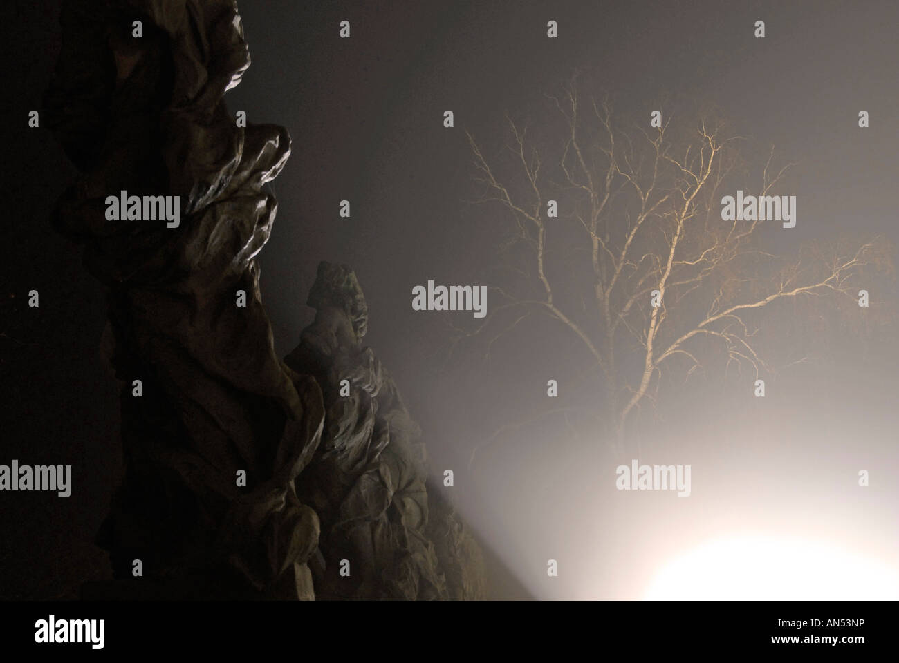 Leafless tree with baroque sculptures lit up at night at the courtyard ...