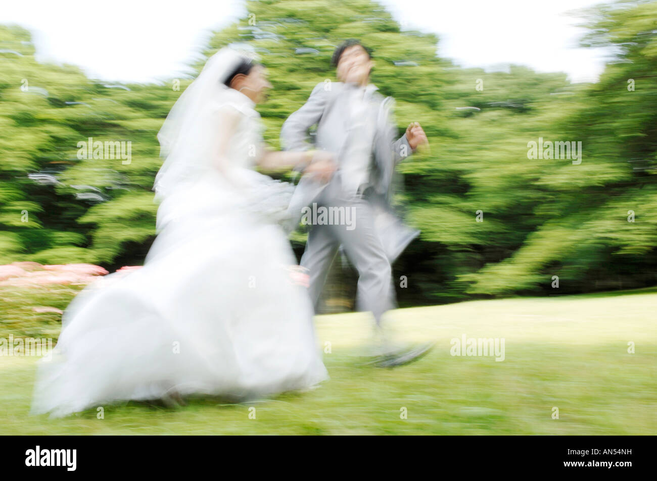 Bridal couple running in garden Stock Photo - Alamy