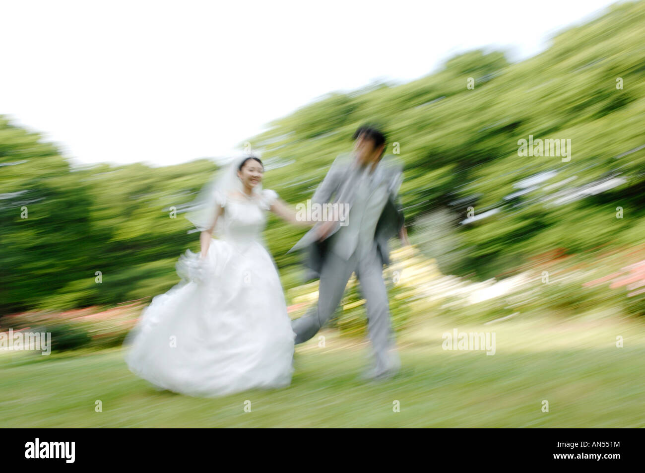 Bridal couple running in garden Stock Photo - Alamy