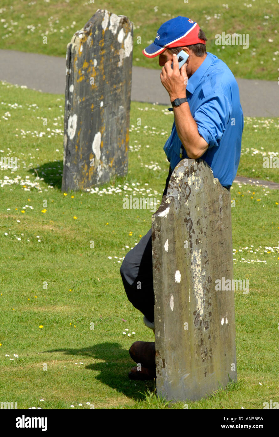 Mobile phone, man leaning on headstone using a mobile phone Stock Photo ...