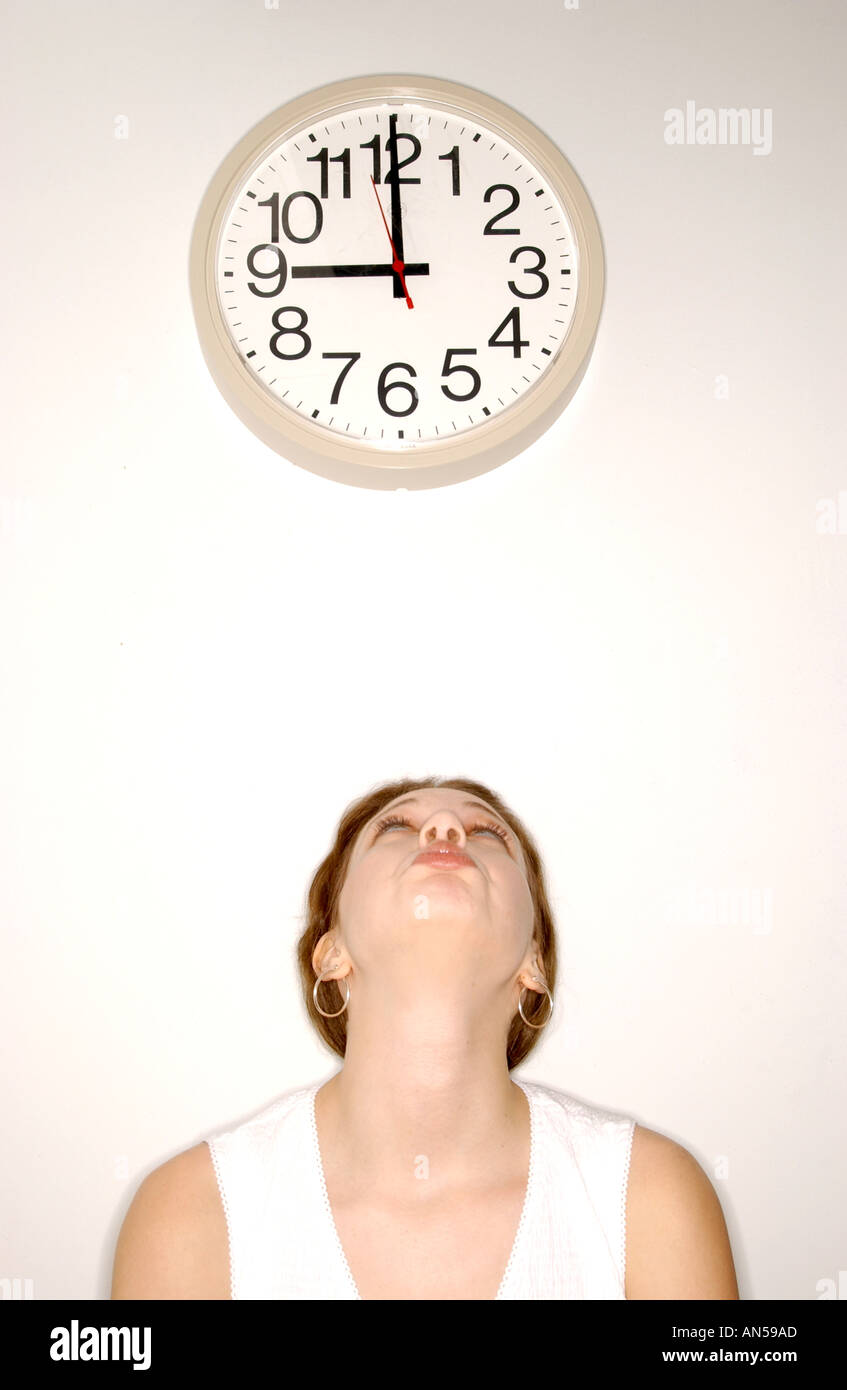 Vertical color image of a brunette adult female looking up at a clock ...