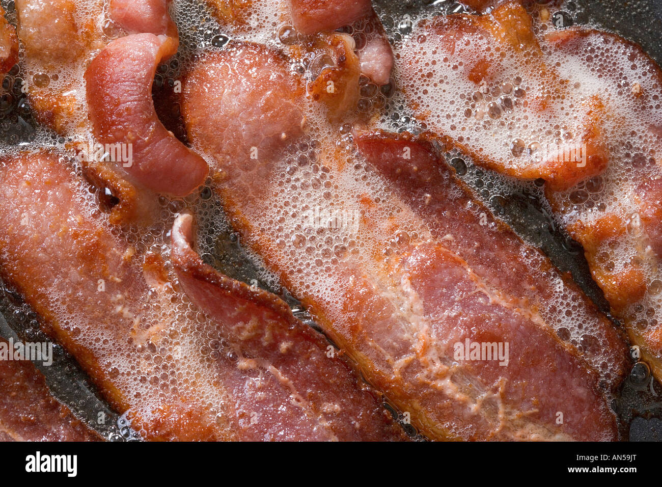 cooking bacon close up showing boiling fat Stock Photo - Alamy