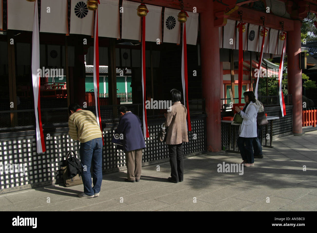 Buddhist Japanese people ring a temple bell and pray at famous Fushimi ...