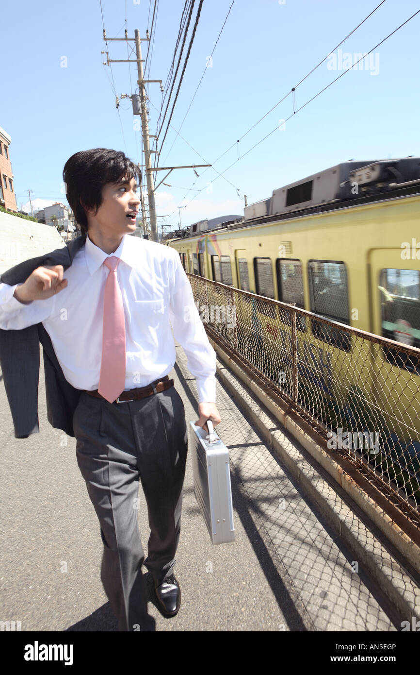 Japanese office worker walking along railroad Stock Photo - Alamy