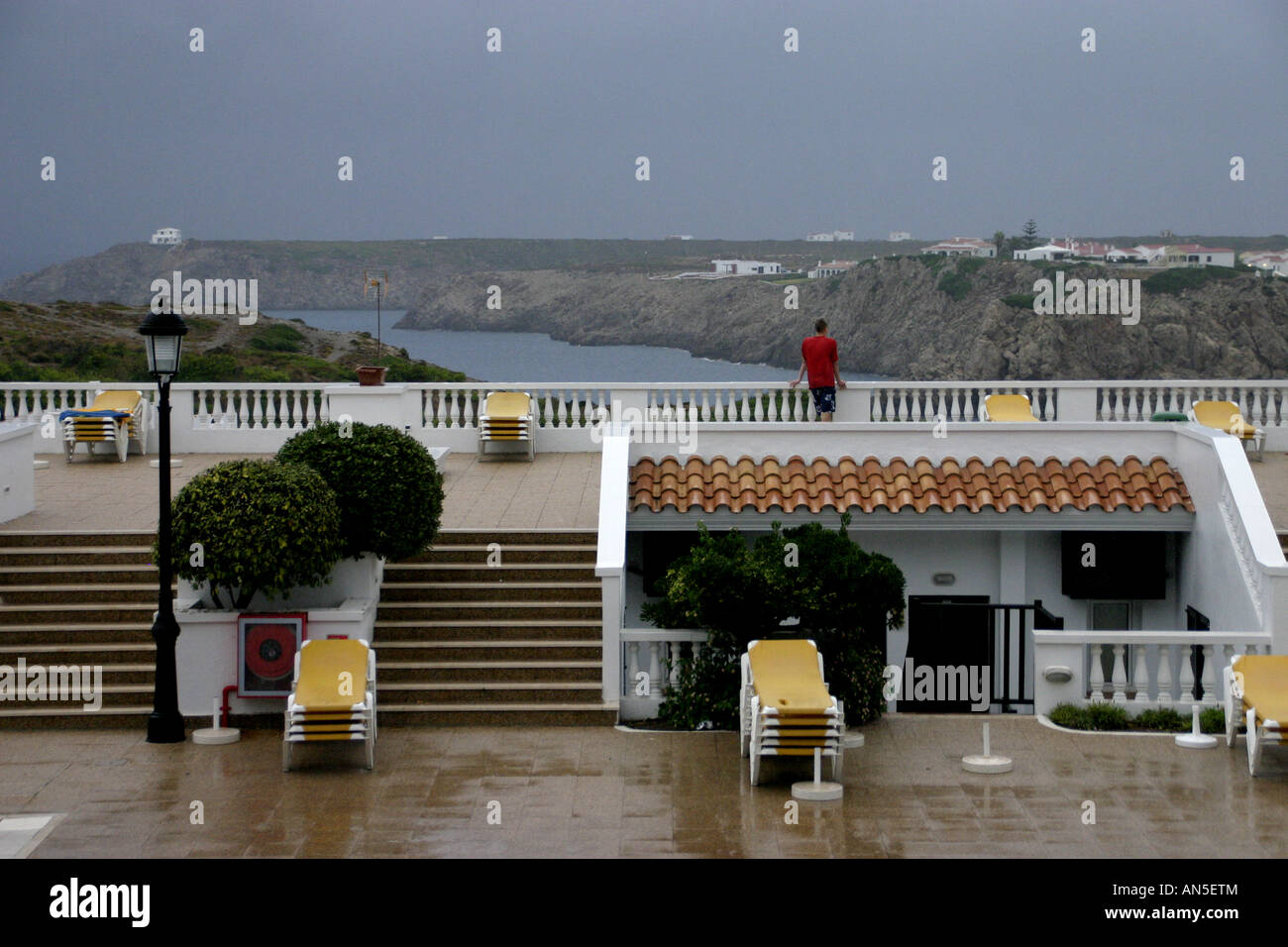 A teenage boy watching heavy rain falling over the bay at Arenal D'en ...