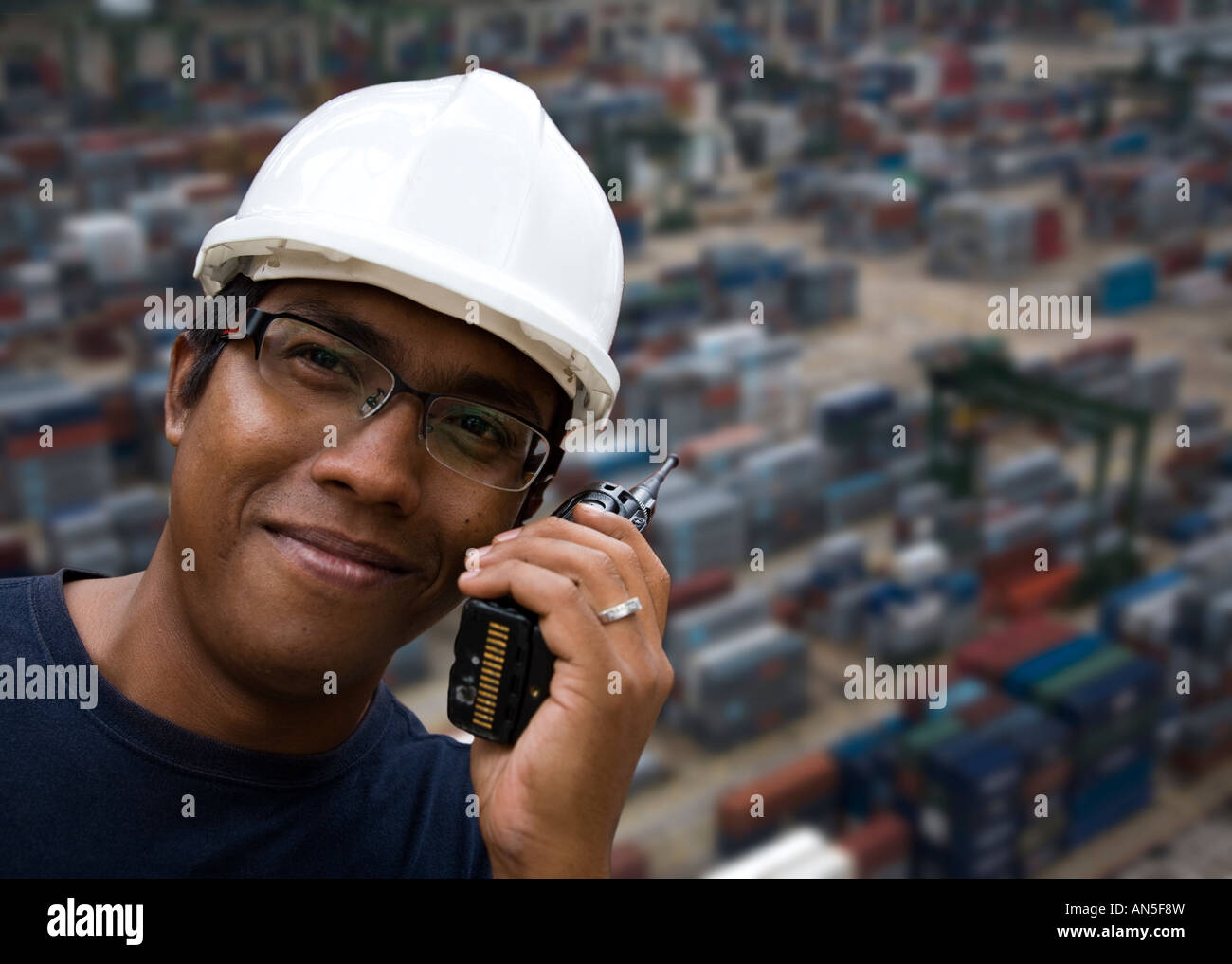 Containerisation stevedore on walkie talkie smiling on top of container ...