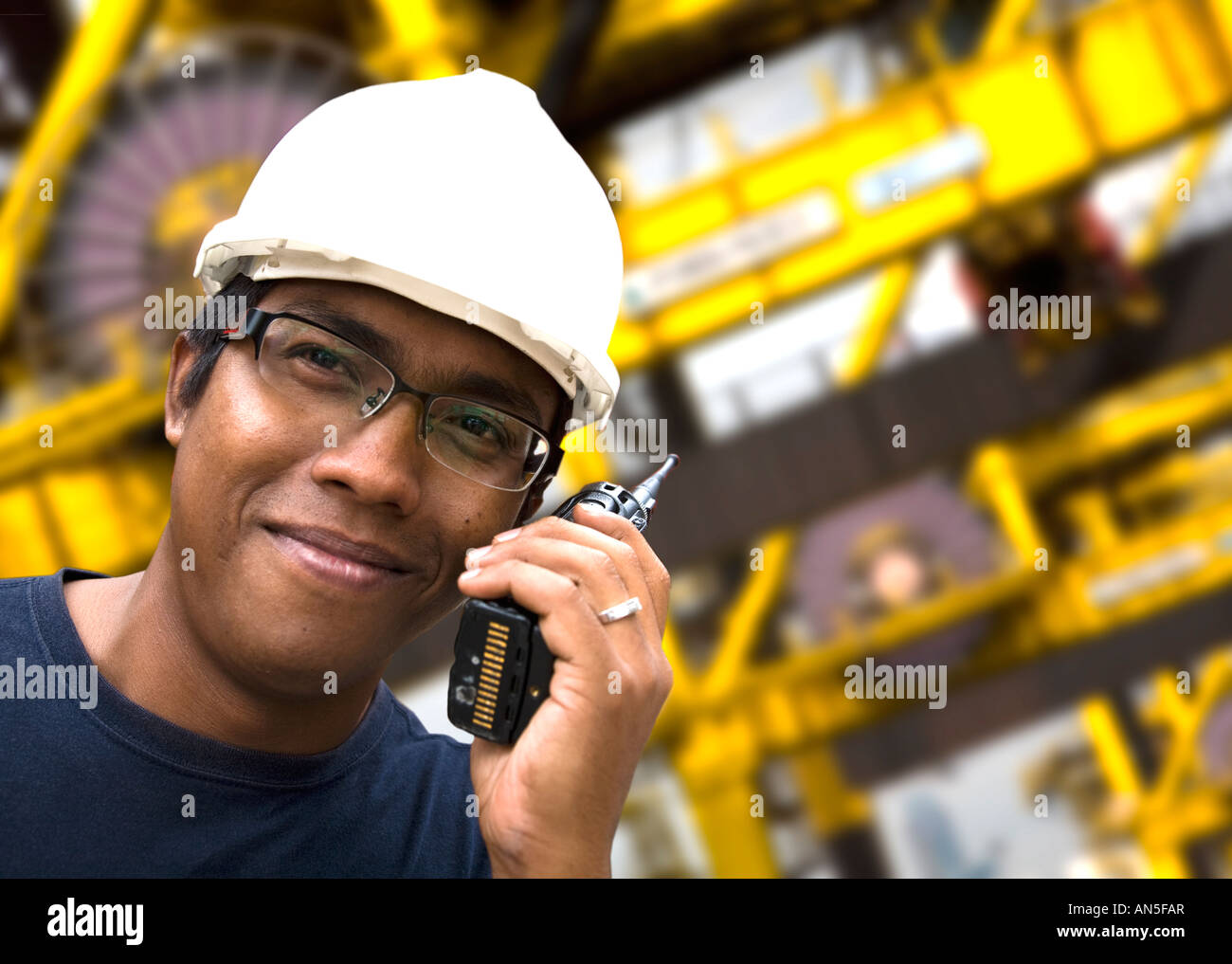 Containerisation stevedore on walkie talkie smiling under container ...