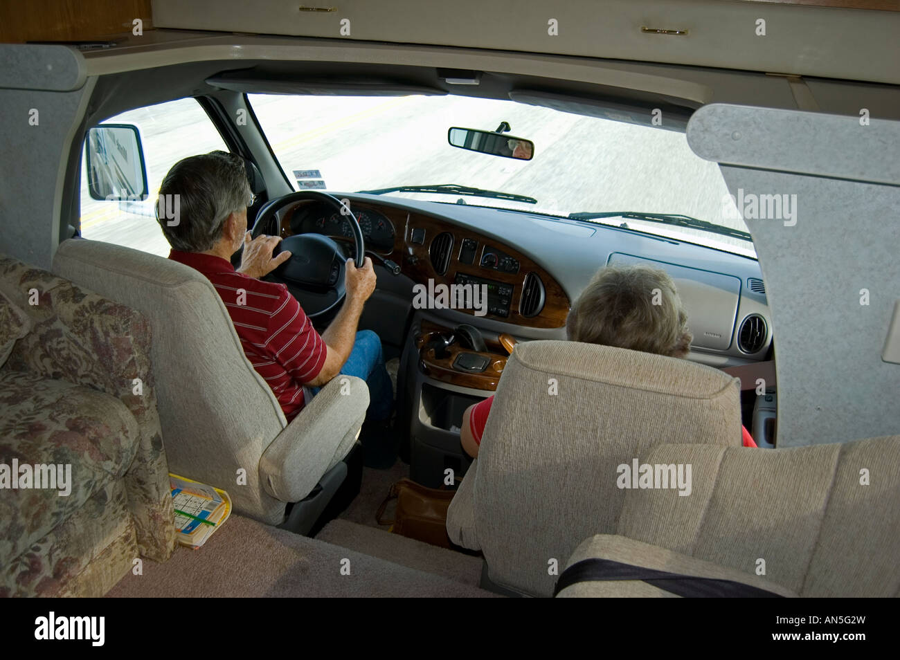 Man and woman in the driver and passenger seats driving their RV on ...