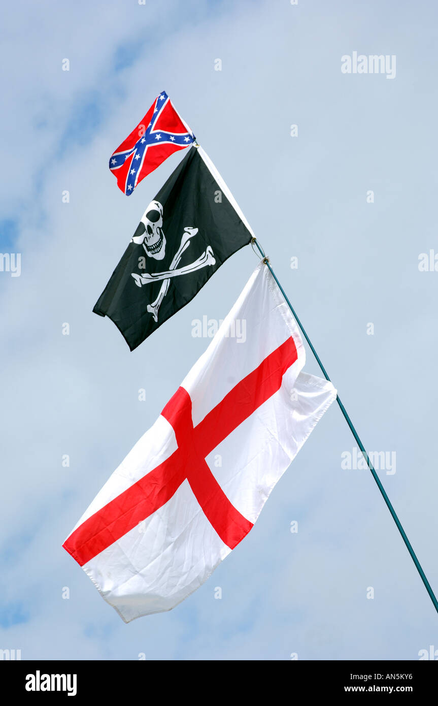 Three flags flying on a single flag pole against a blue cloudy sky flag ...