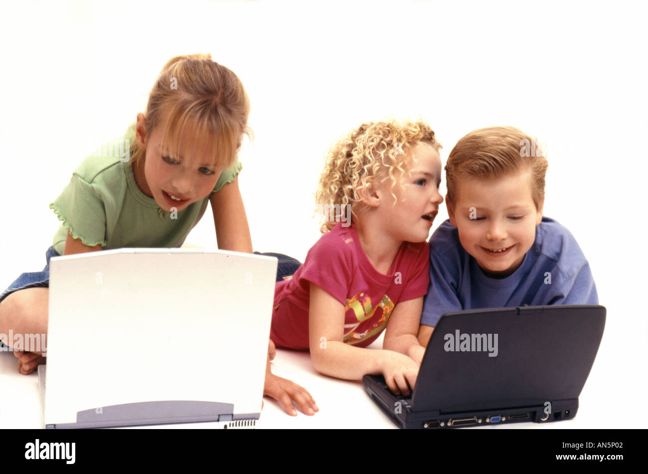 Three young kids play on laptops Stock Photo - Alamy