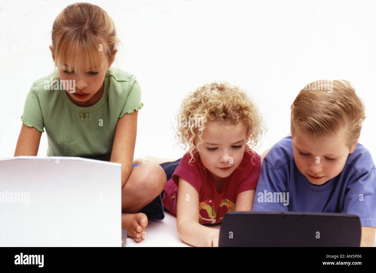 Three young kids play on laptops Stock Photo - Alamy