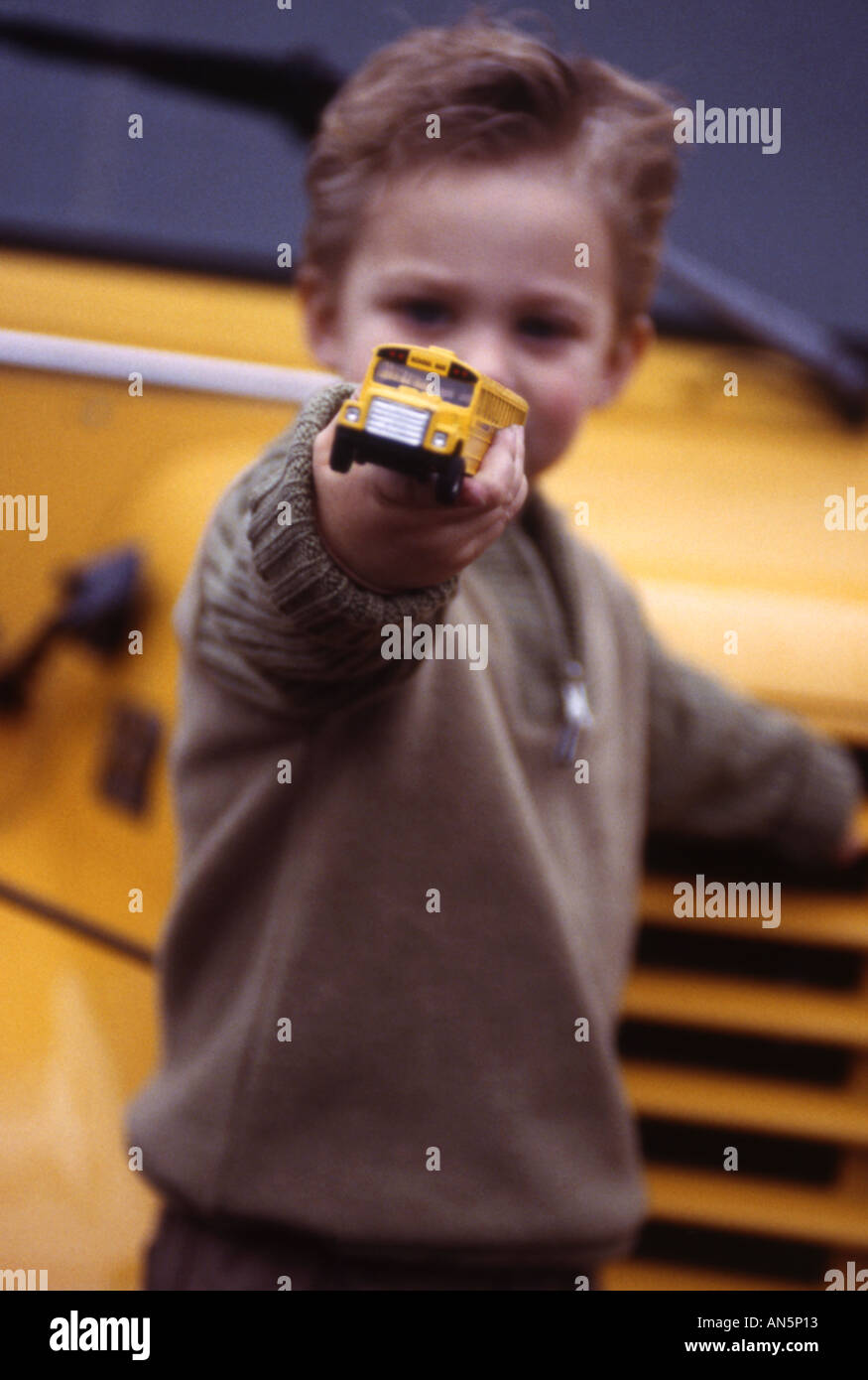 Young boy playing with toy school bus in front of real bus Stock Photo ...