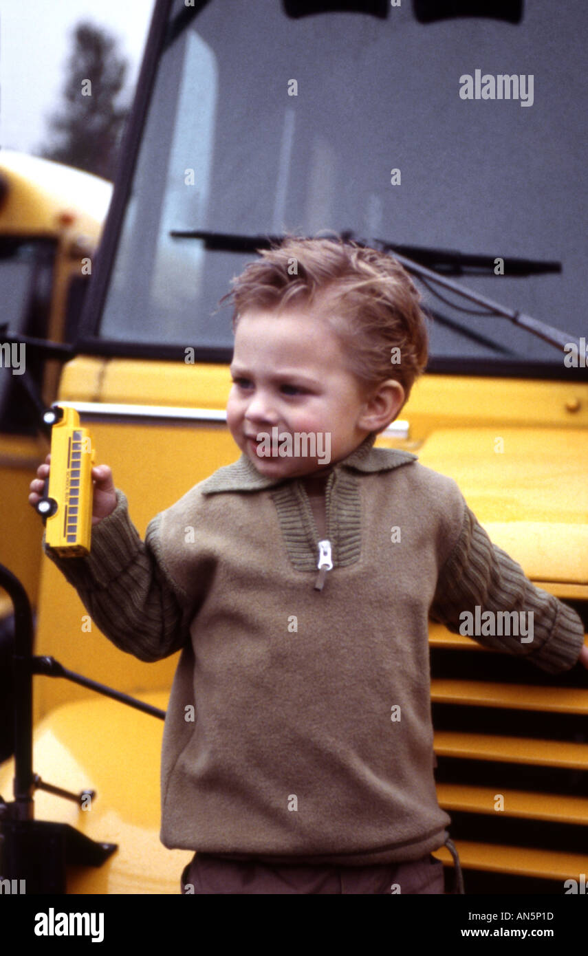 Young boy playing with toy school bus in front of real bus Stock Photo ...