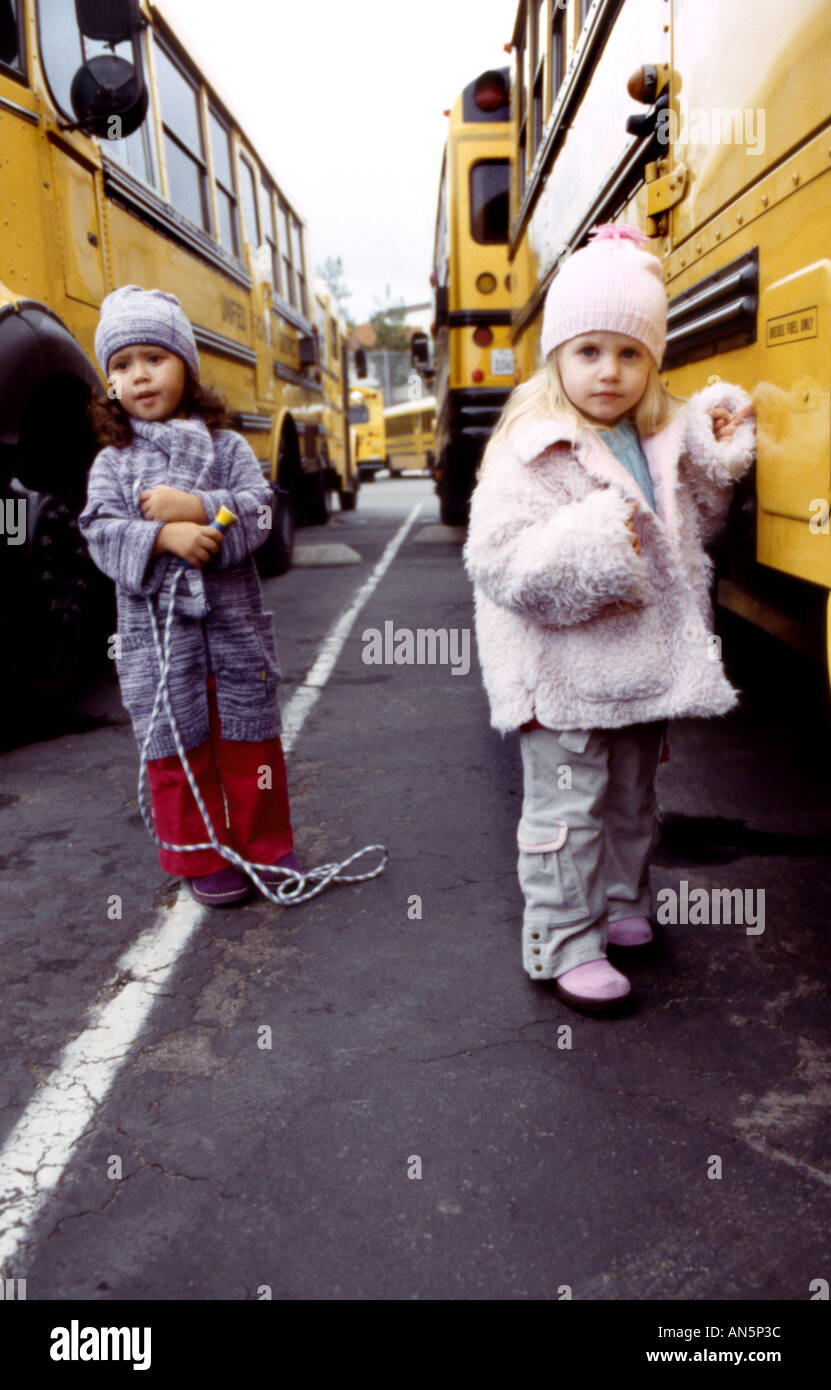 Two young girl poses in front of a school bus Stock Photo - Alamy