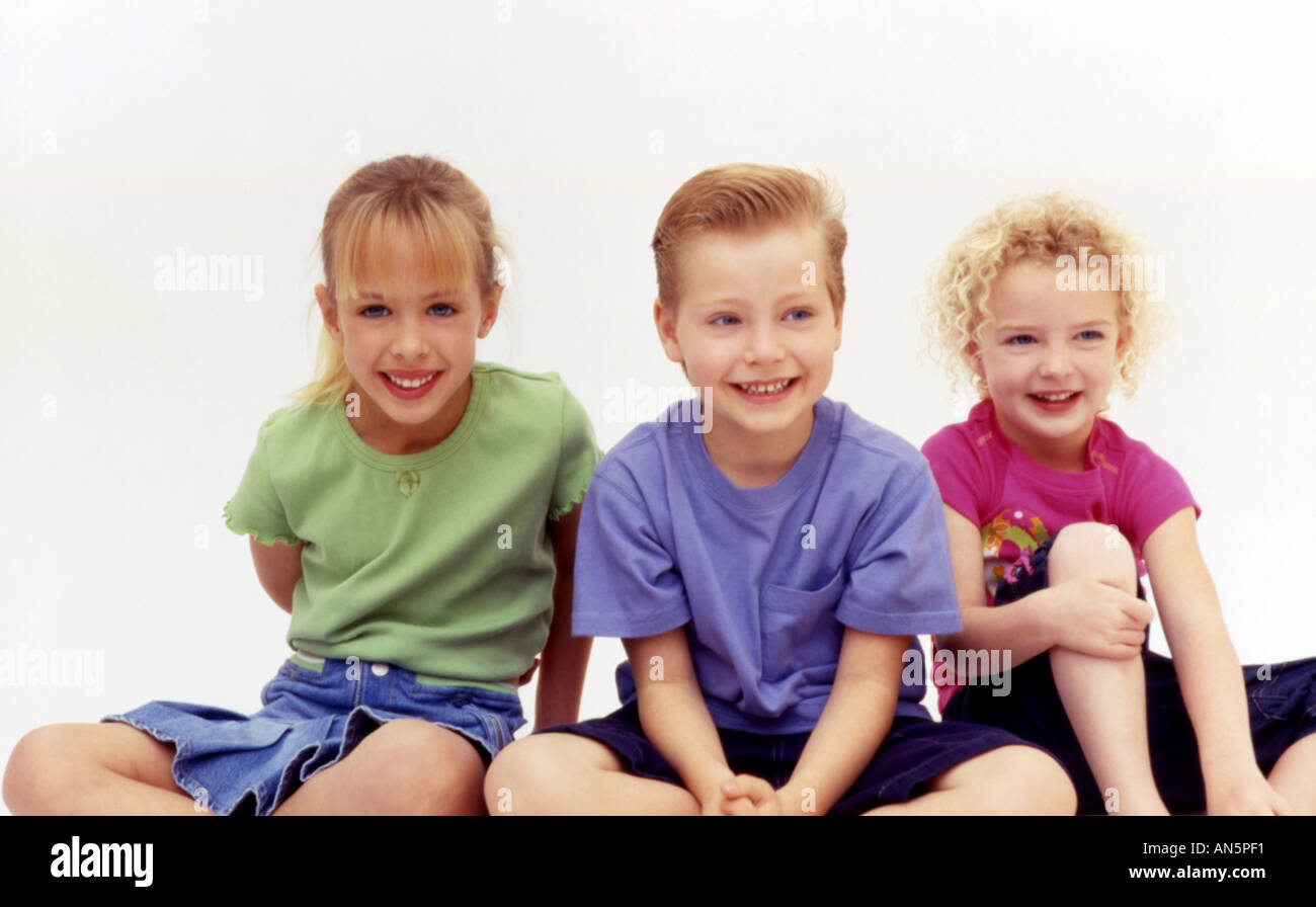 Three young children sitting happily Stock Photo - Alamy