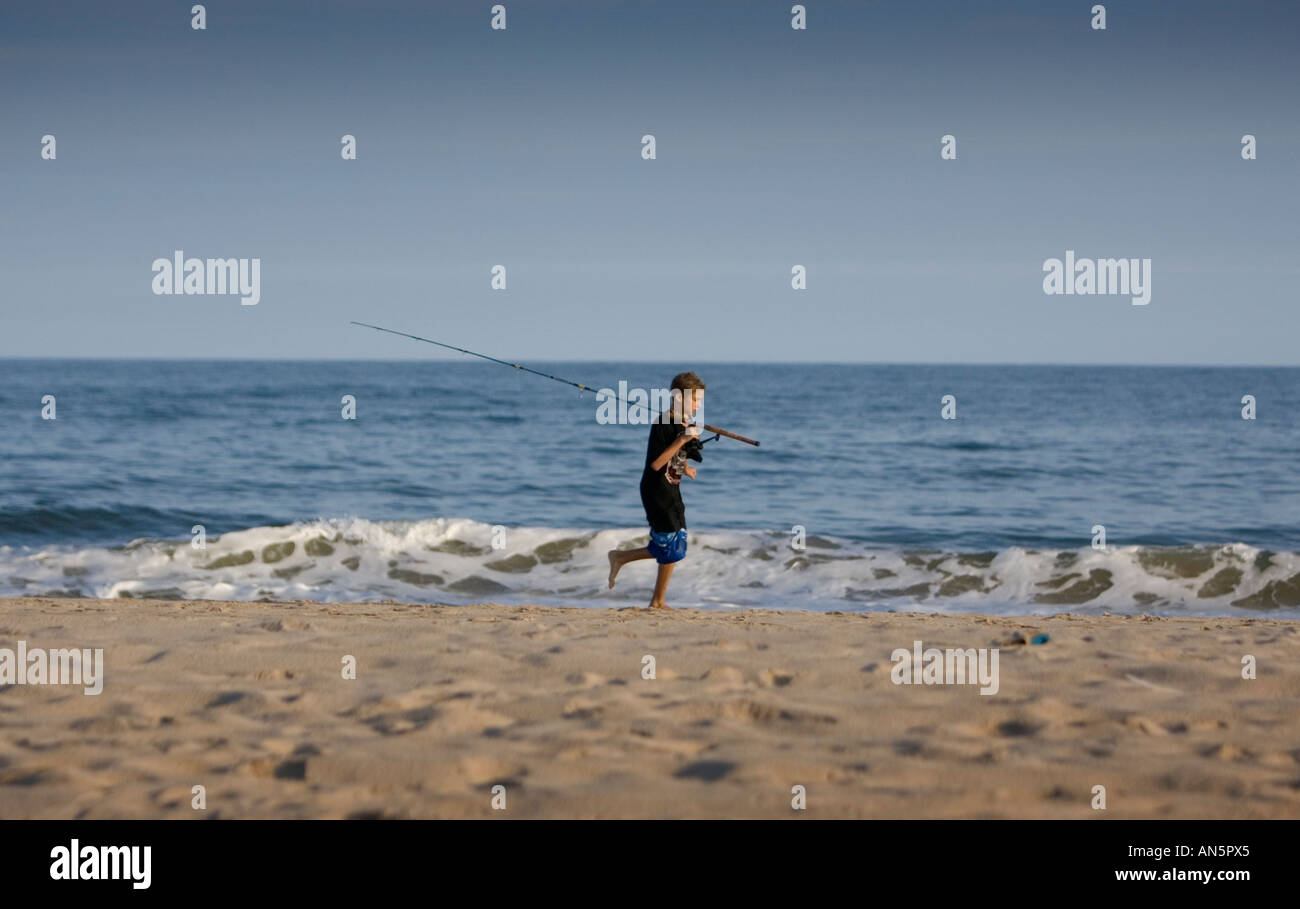 Boy carrying a fishing rod on the beach Stock Photo - Alamy