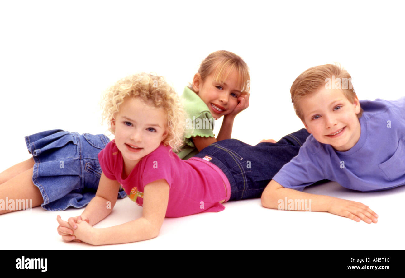 Three young children laying on the floor smiling Stock Photo - Alamy