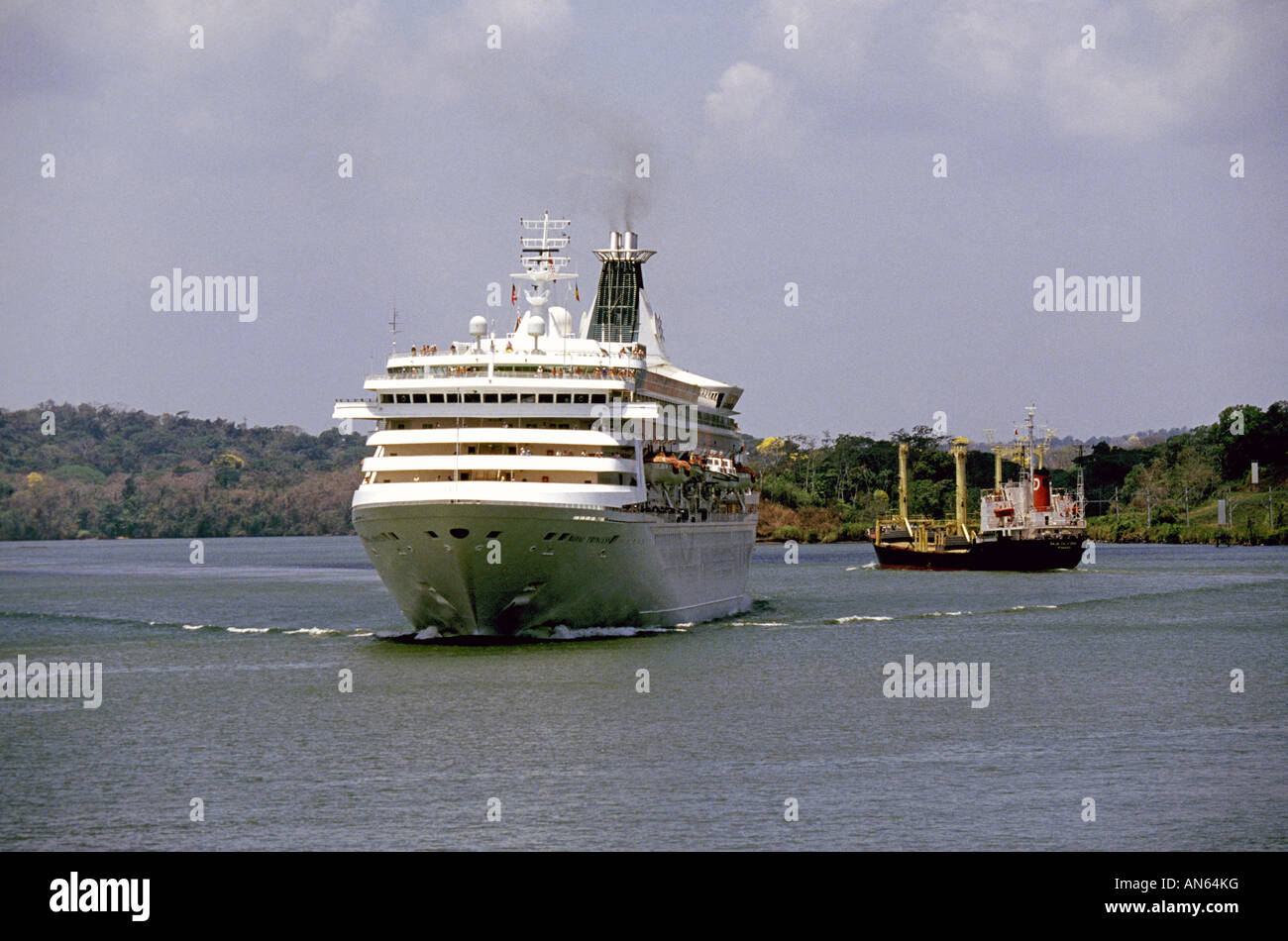 A large passenger cruise ship and a cargo ship make a daylight passage ...