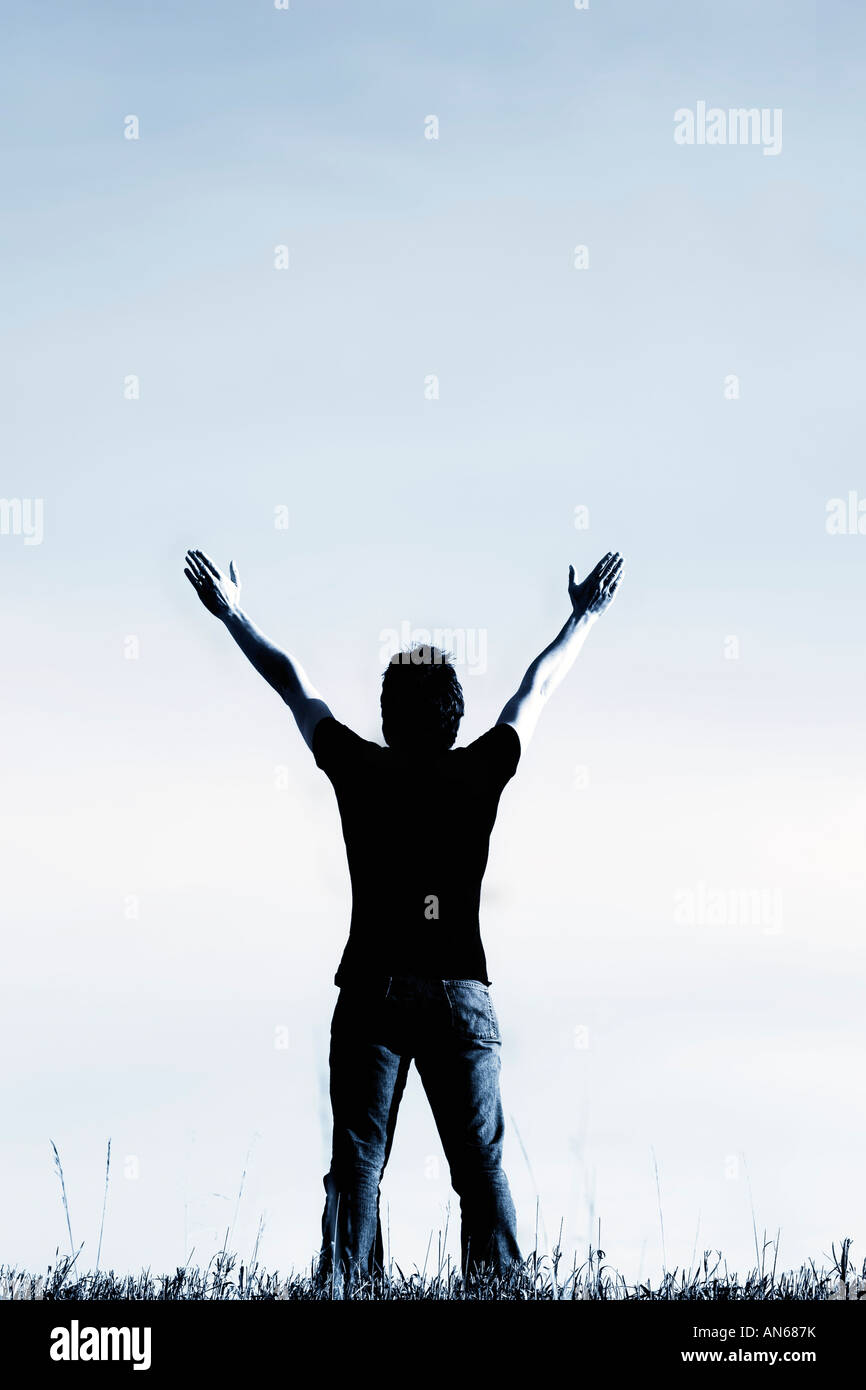 Man standing with arms raised Stock Photo - Alamy
