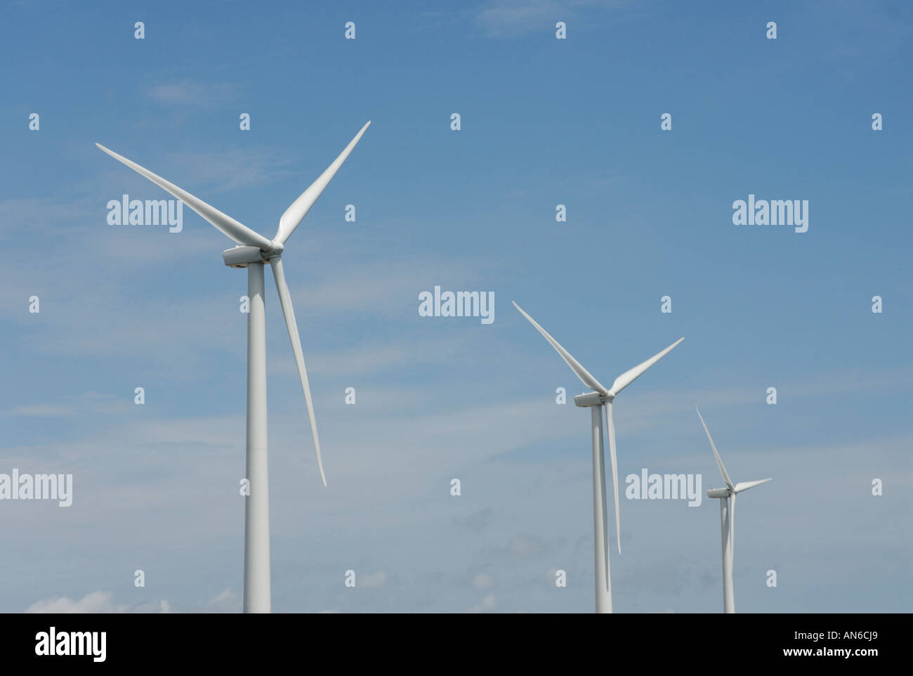Three wind turbines, close-up of blades, against blue sky. Wind power ...