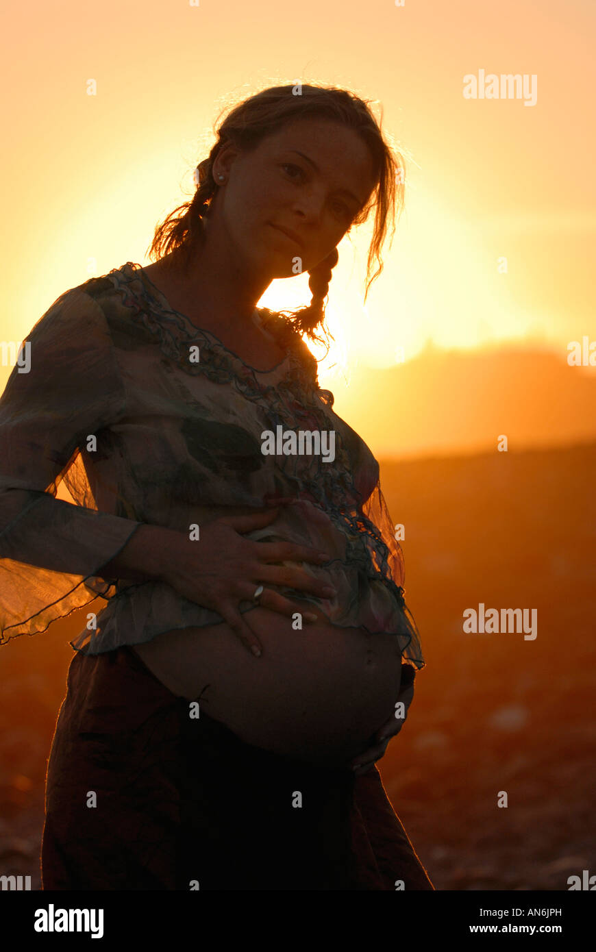Young pregnant women on beach holding stomach at sunset Stock Photo - Alamy