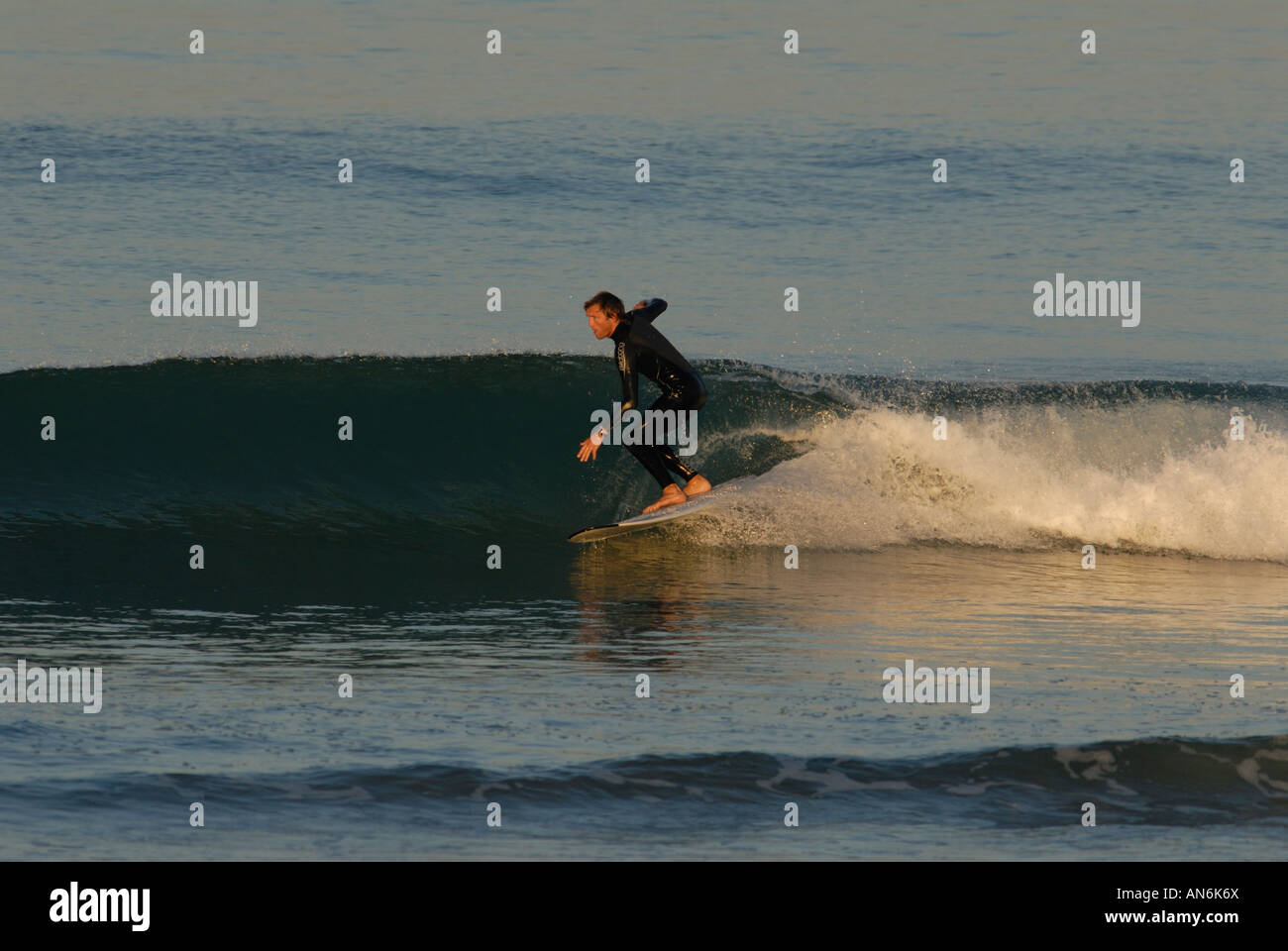 Surfer riding the nose of his malibu board at small beach break wave at ...