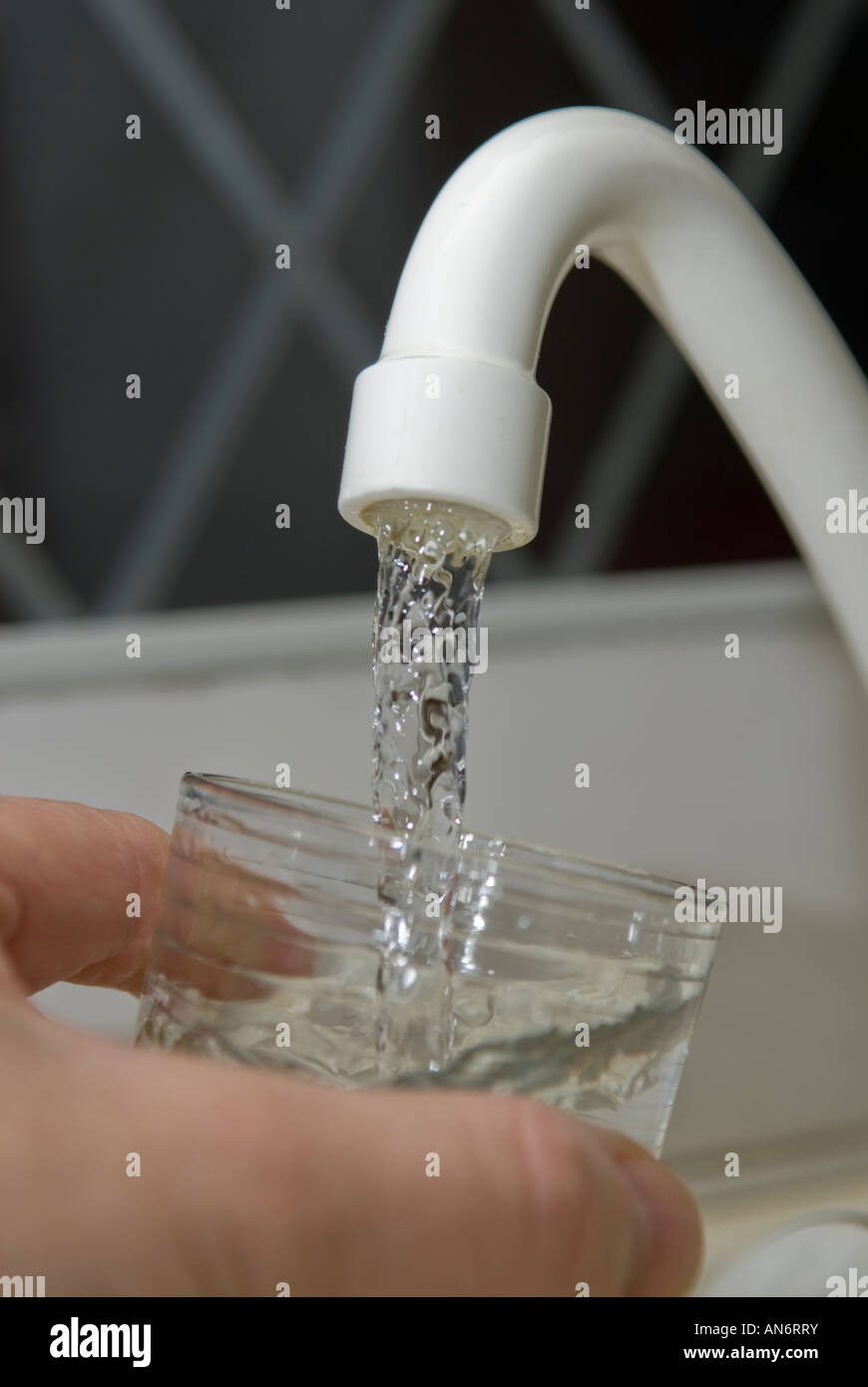 Filling a glass with water from kitchen tap with a hand holding the ...