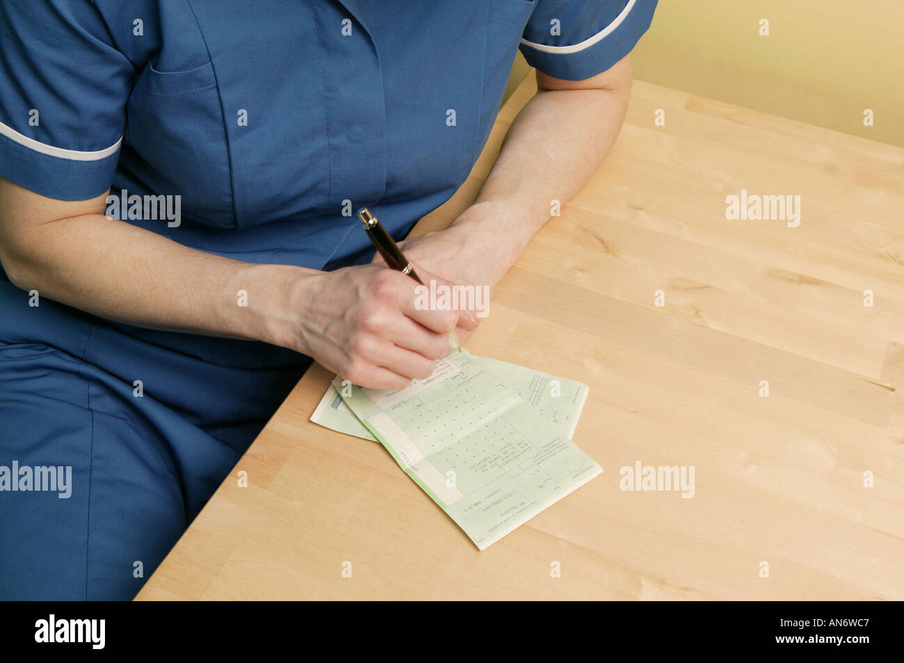 NHS nurse wearing blue uniform writing out a prescription Stock Photo ...