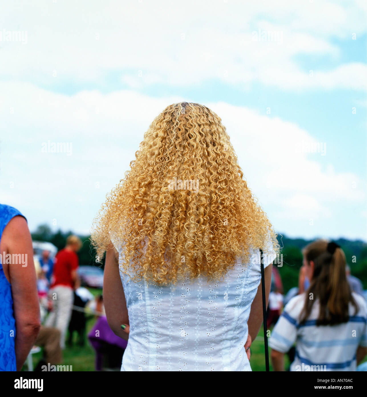 A rear view of a young woman with frizzy bleach blonde hair style ...