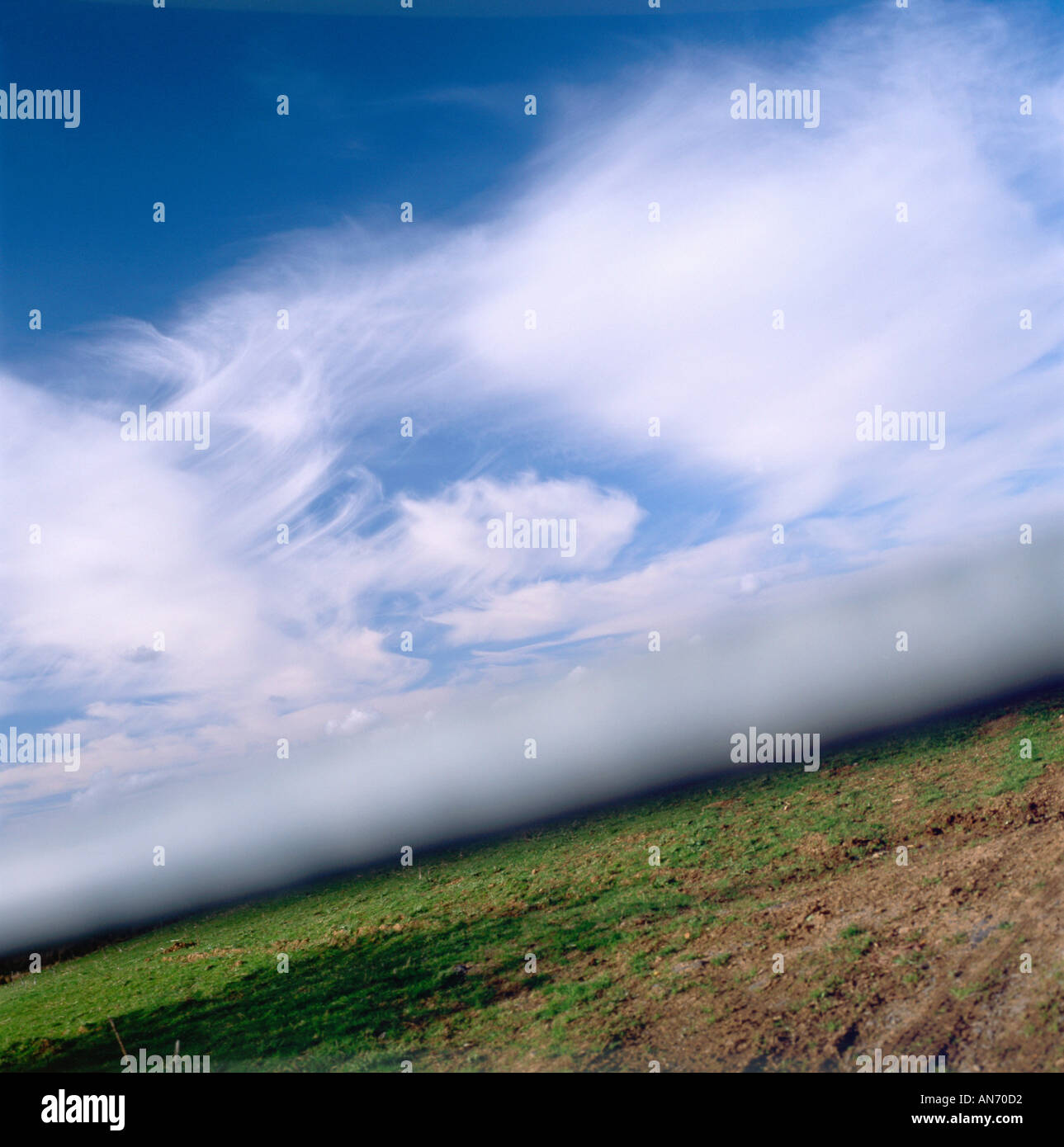 Farming landscape showing the blurred top rail of a gate against a blue ...