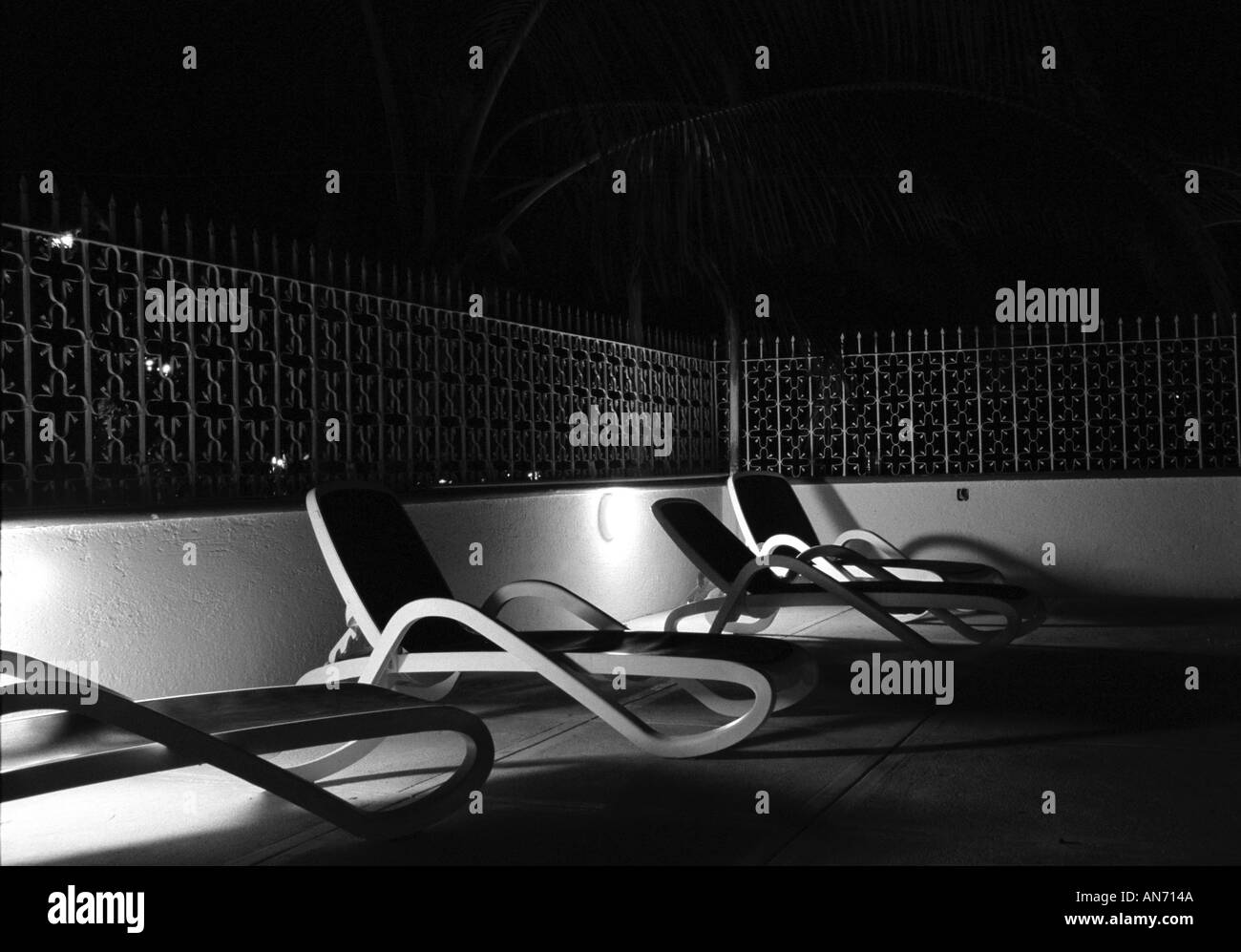 Beach chairs at a pool at night Stock Photo - Alamy