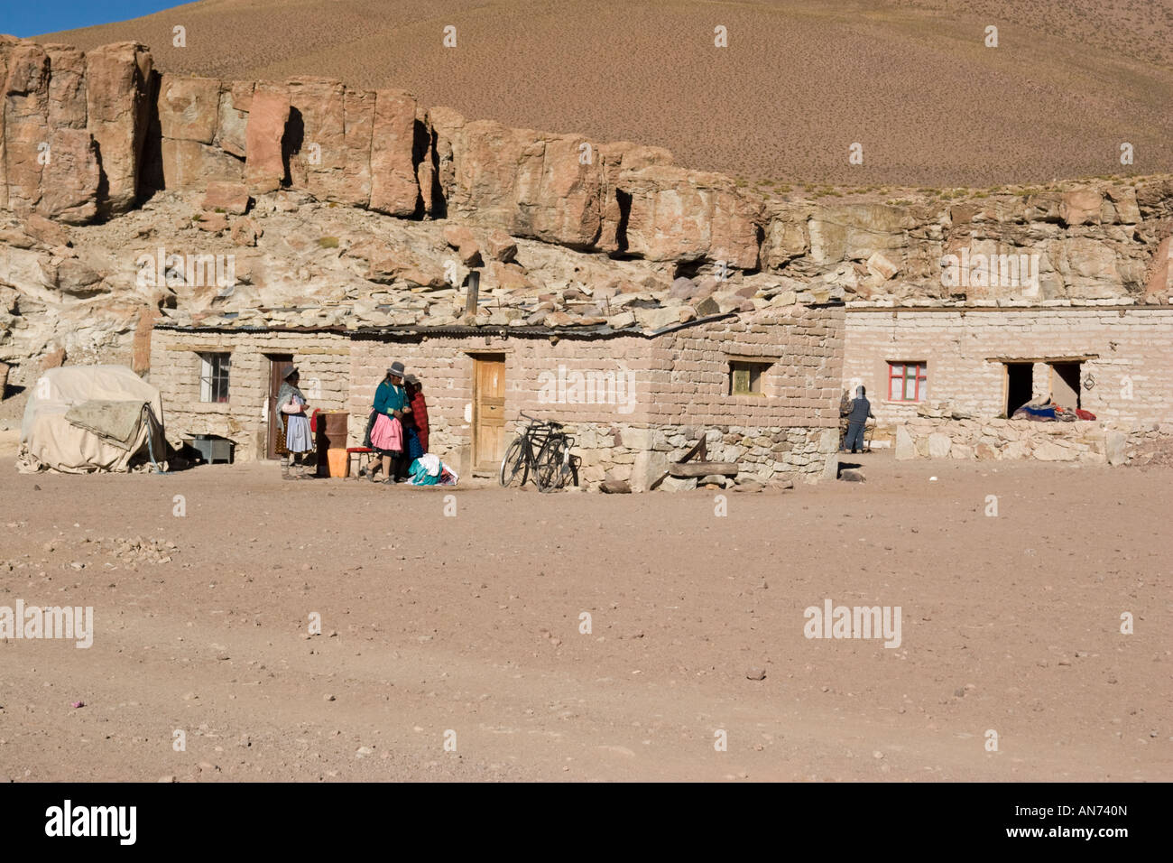 Bolivian Aymara village women and bicycle outside a mud brick house in ...