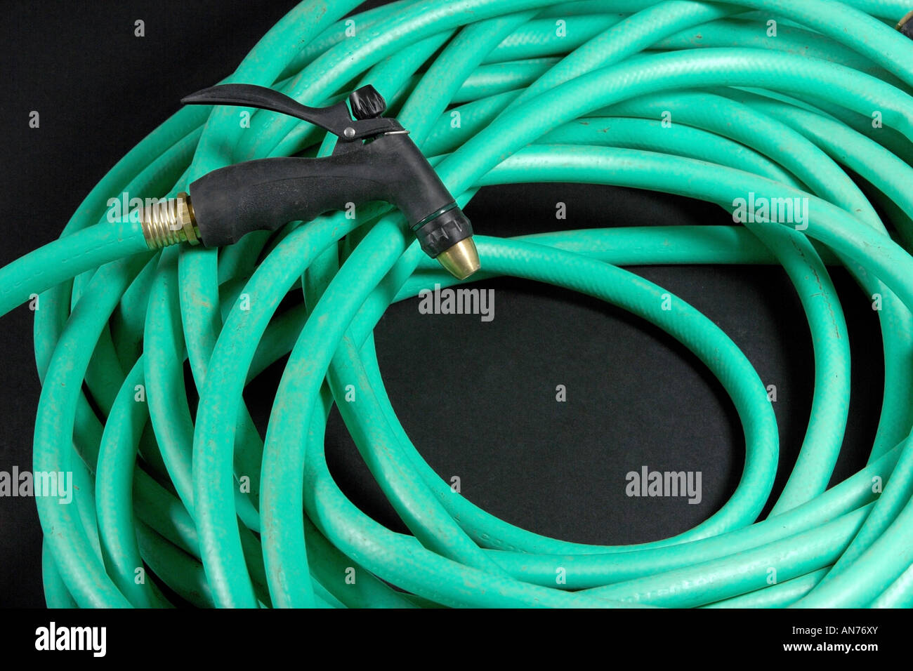 A garden hose coiled with a sprayer Stock Photo - Alamy