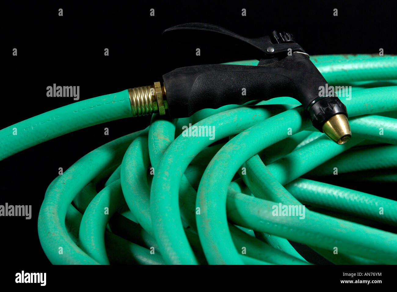 A garden hose coiled with a sprayer Stock Photo - Alamy