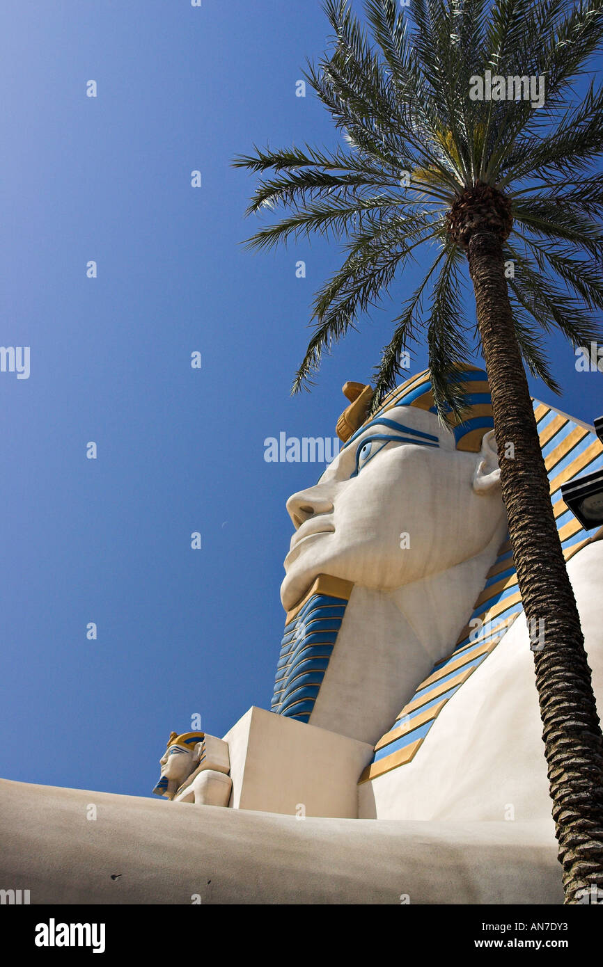 Blue white and gold sphinx statue framed by palm trees and backed with ...