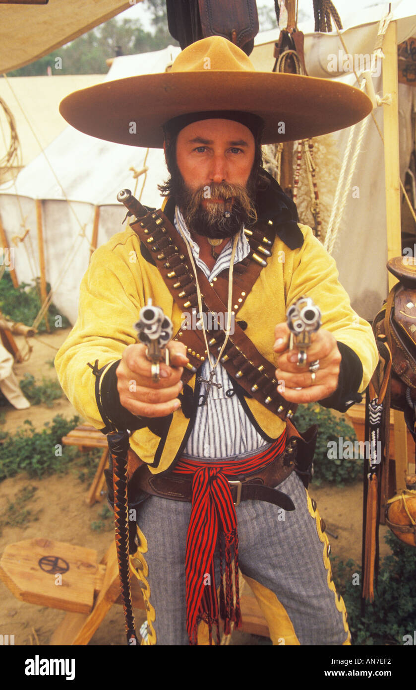 Reenactor dressed as a bandito of the Old West pointing his six guns at ...