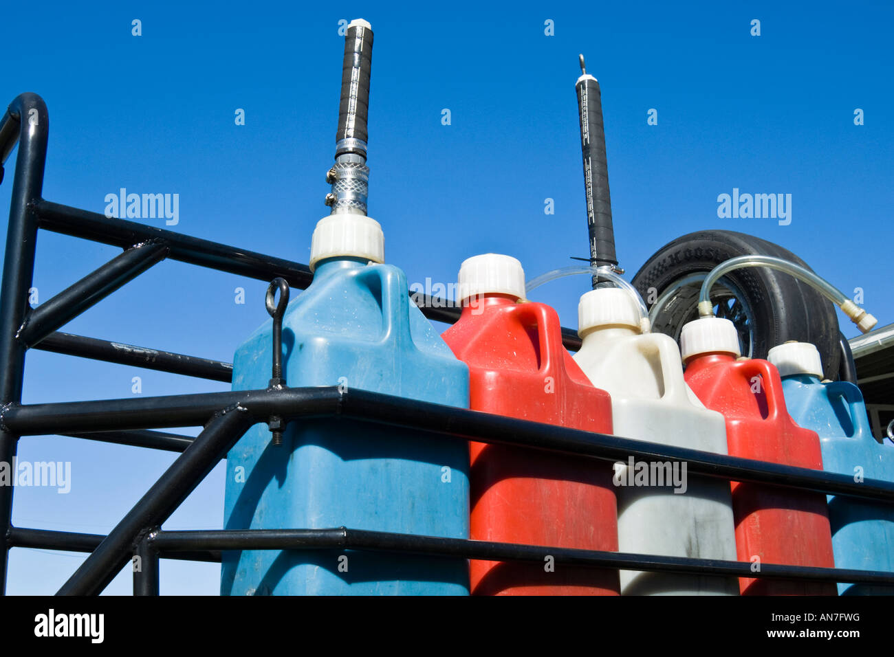 Red white and blue motor racing fuel containers some with spouts lined ...