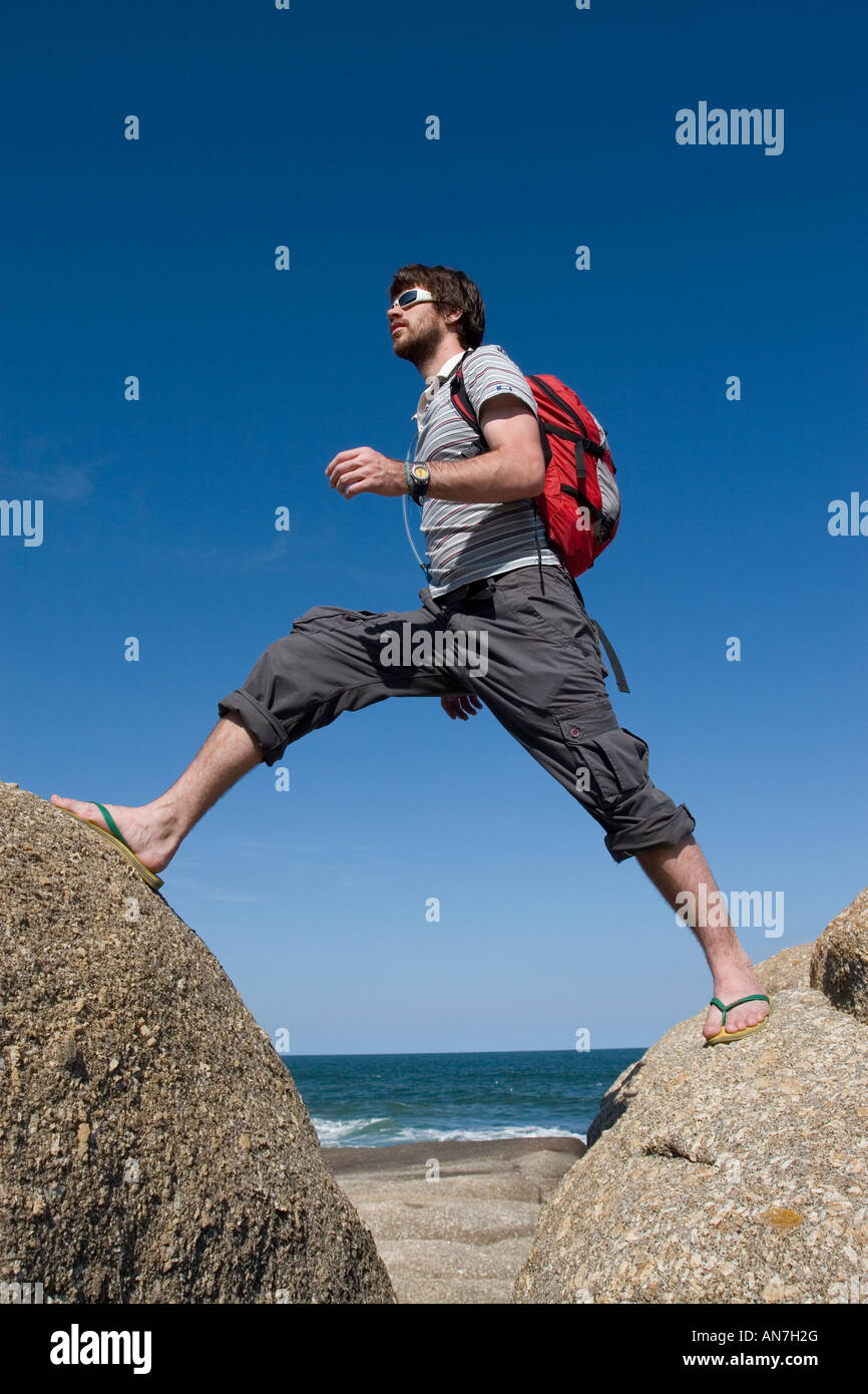 Man Stepping Across Rocks on Beach Stock Photo - Alamy