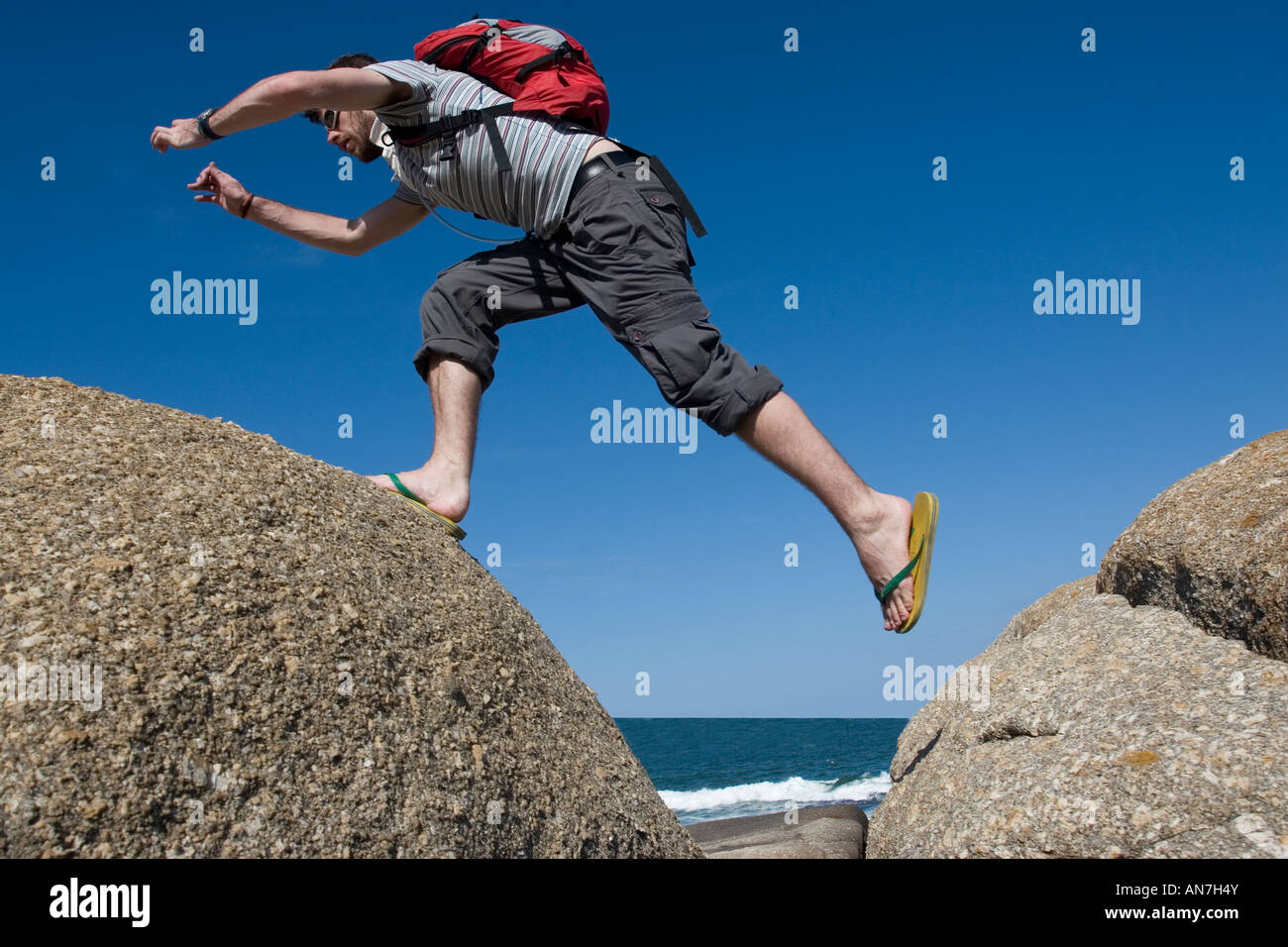 Man Stepping Across Rocks on Beach Stock Photo - Alamy