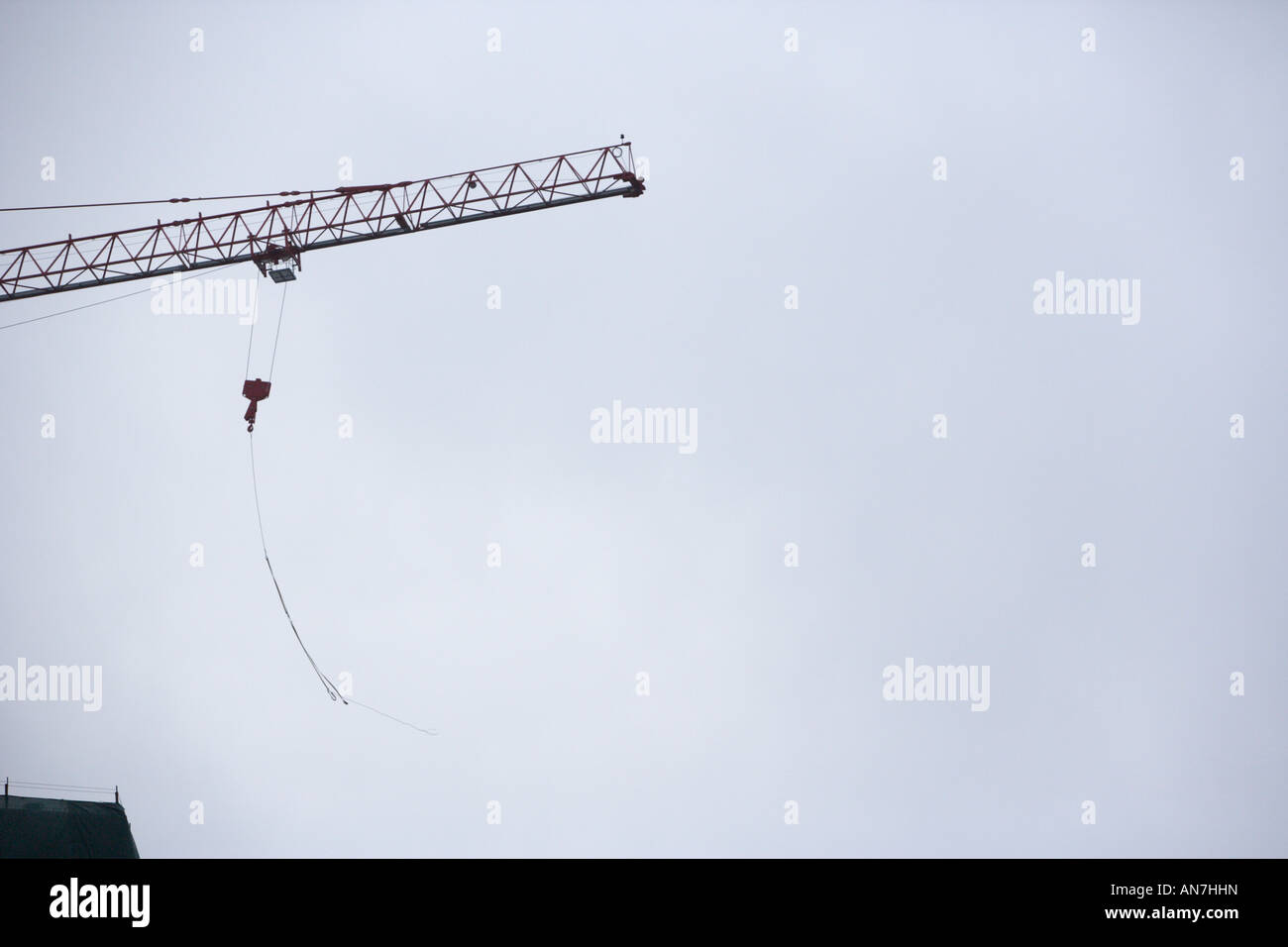 A crain at a construction site lifts building material to the top of a ...