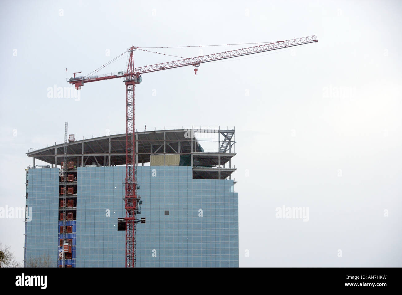 A crain at a construction site lifts building material to the top of a ...