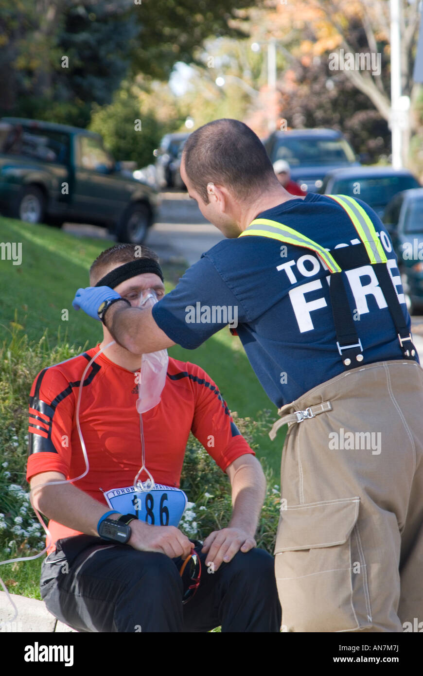 Fireman performing emergency first aid on marathon runner in Toronto ...