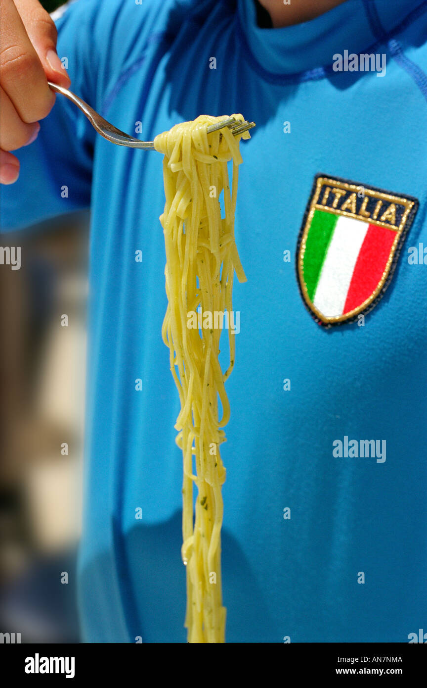 Teenage boy's hand holding fork with pasta dangling Stock Photo - Alamy