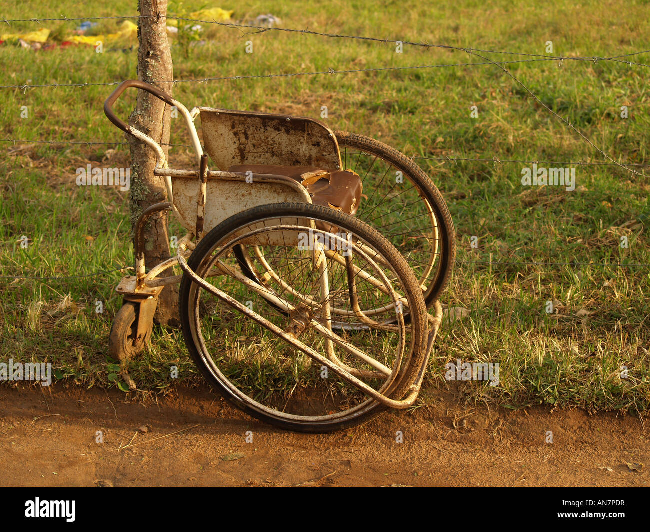 Rusty wheelchair by barbed wire fence Stock Photo - Alamy