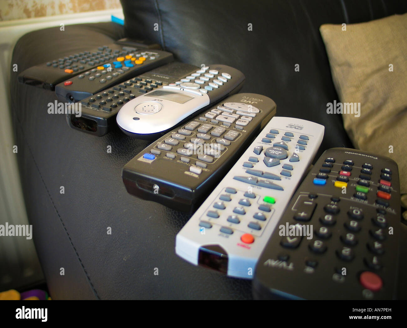 Remote controls arranged on the arm of a sofa Stock Photo - Alamy