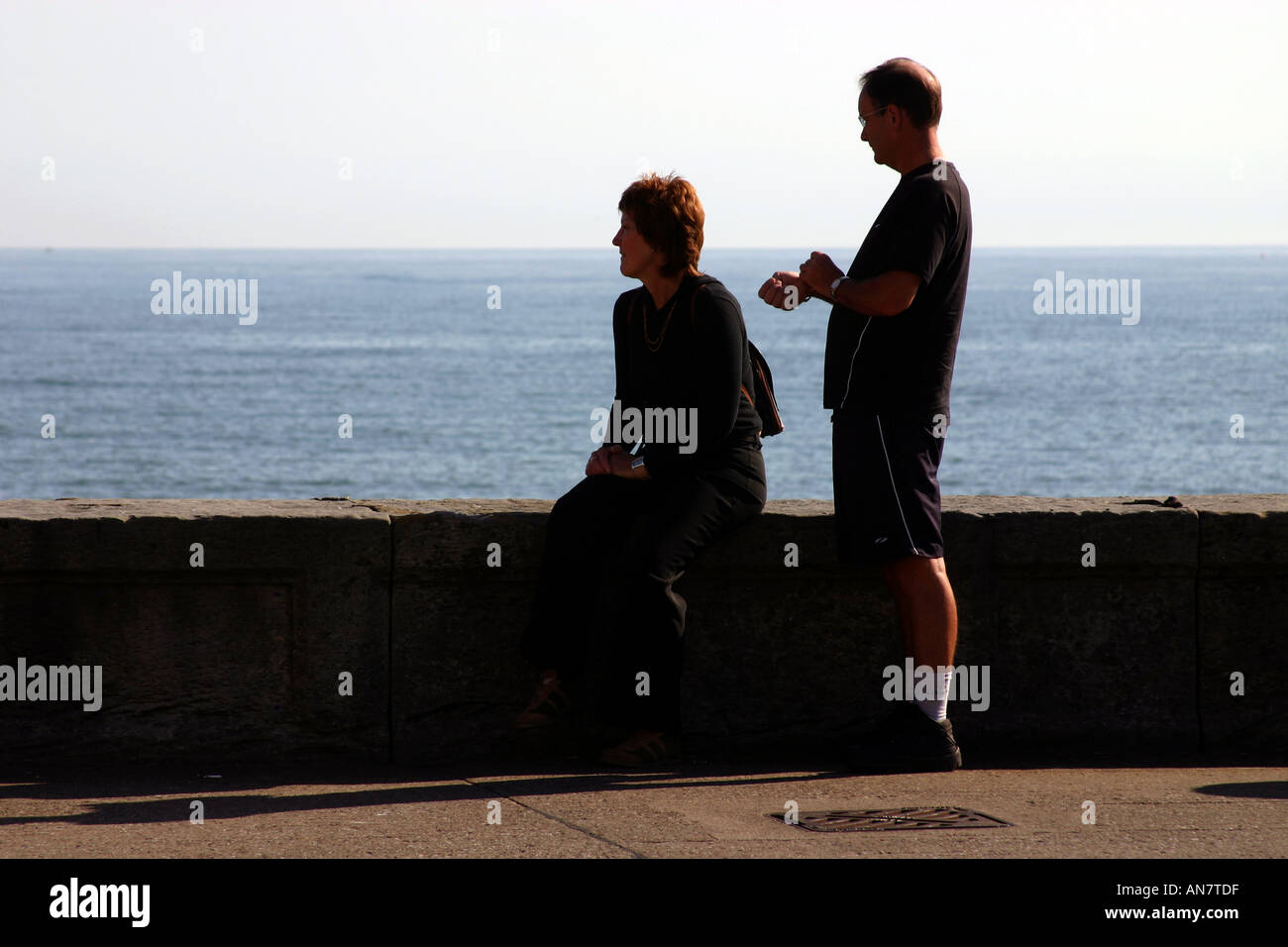 Silhouette of couple on cliff top looking out to sea Stock Photo - Alamy