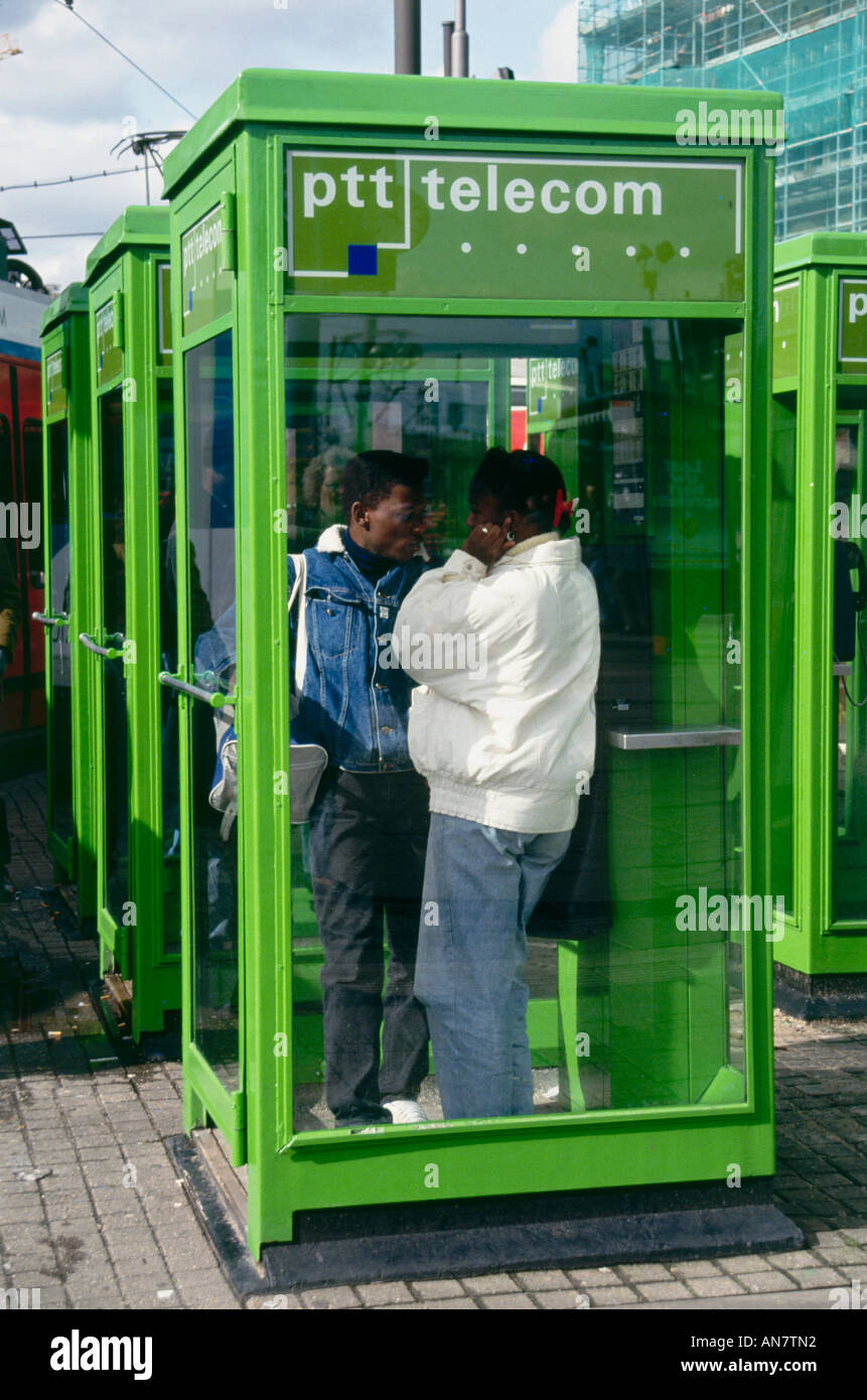 People making use of one of a group of green painted telephone boxes ...
